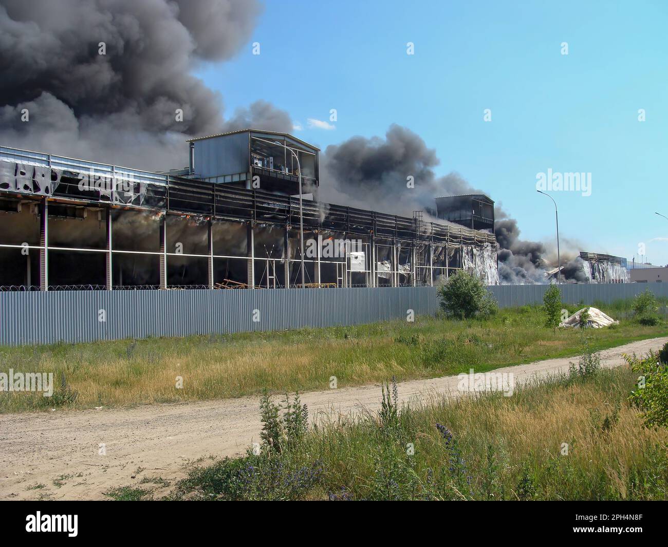 Warehouse fire with black thick smoke against a clear sky. Sandwich ...