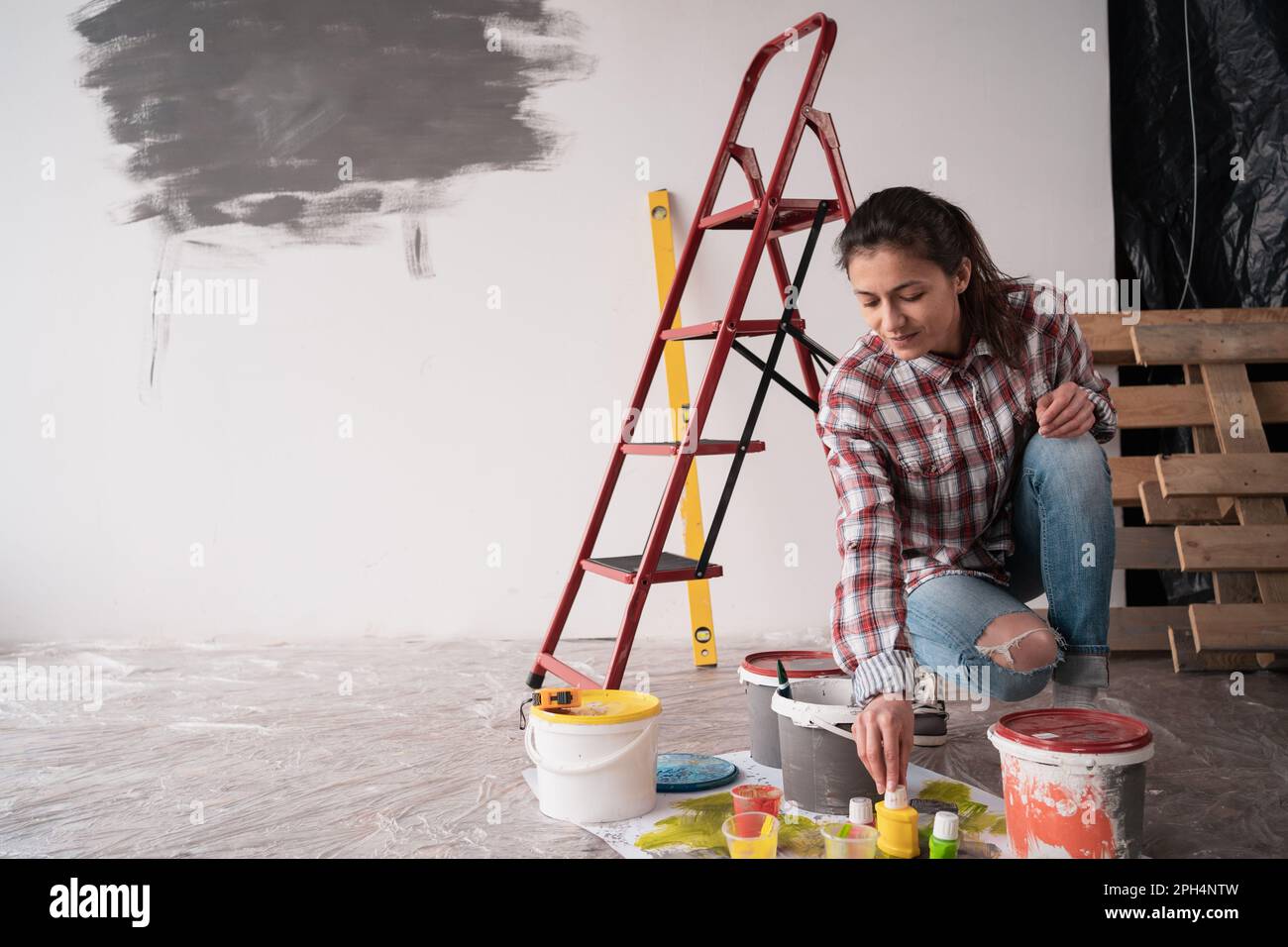 Woman working making home repair painting wall choose paint cans and ...