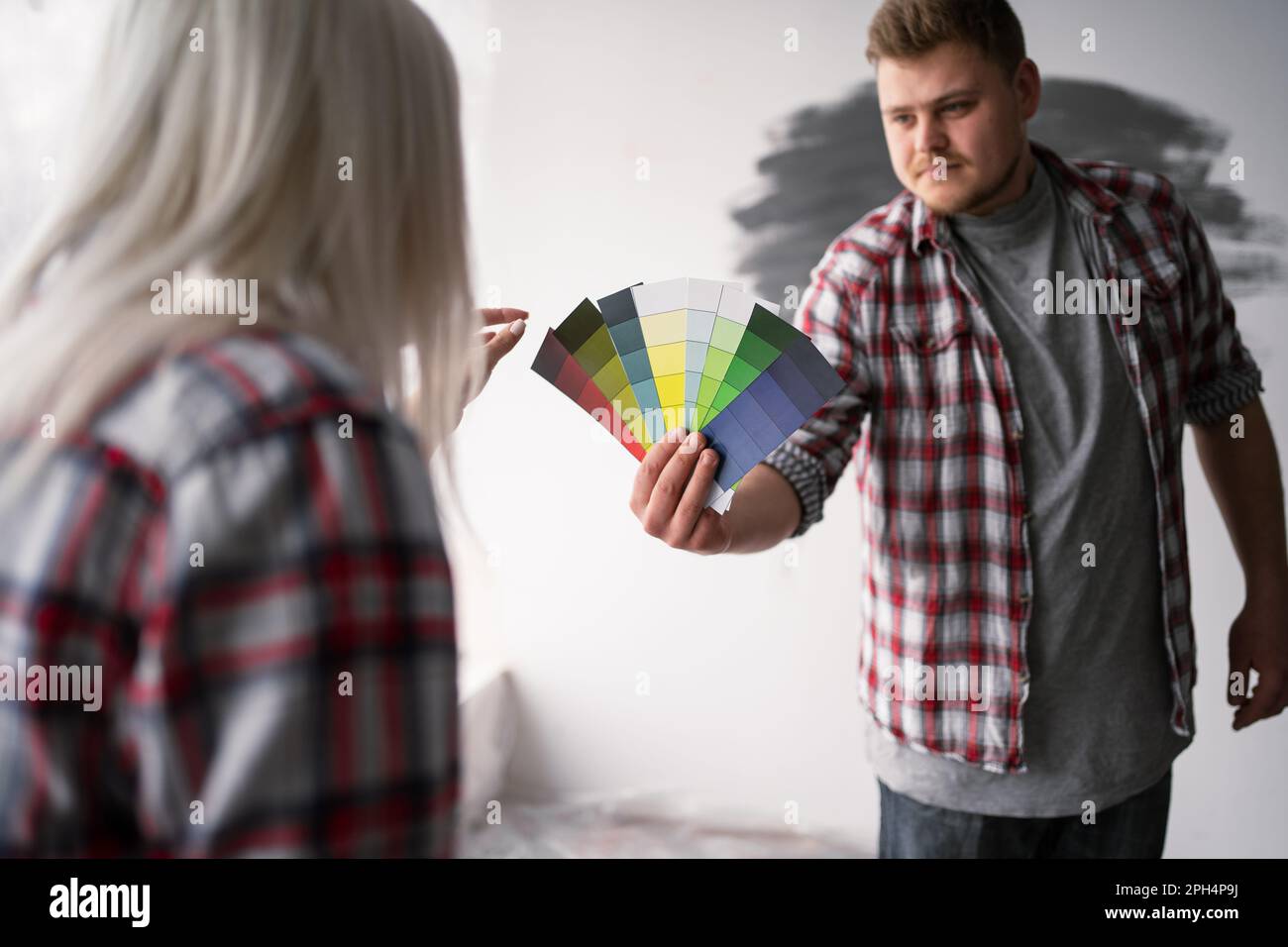 Smiling couple looking at color samples at home and choose from palette ...