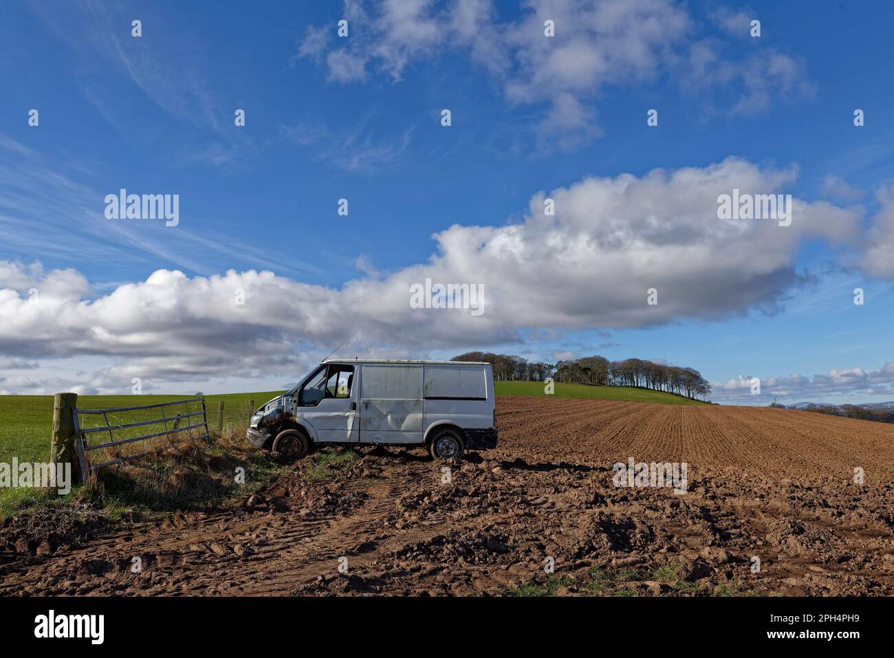 A damaged and abandoned White Van parked in a ploughed field near to ...