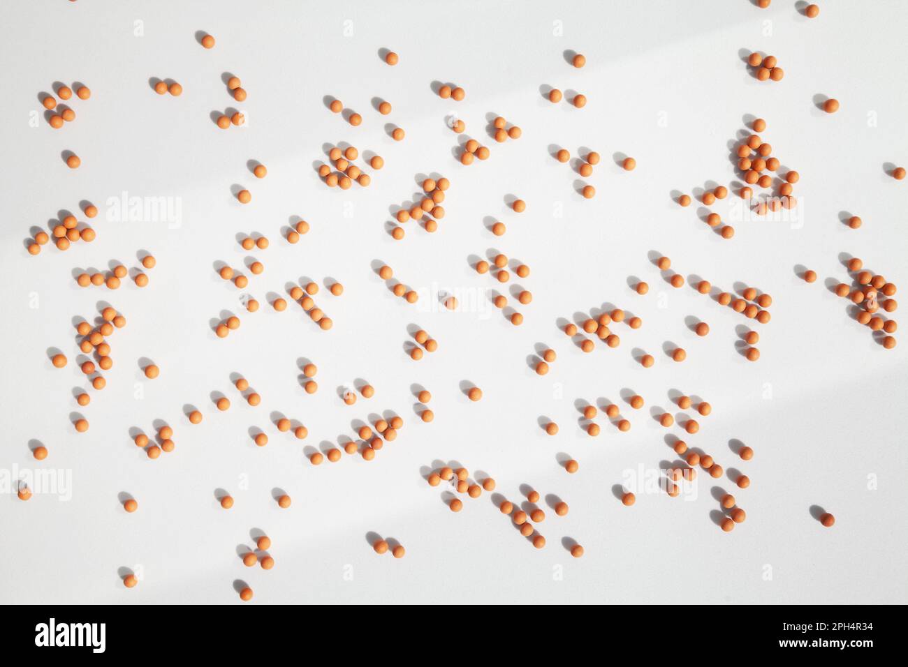 Many little orange balls scattered on a white background in the bright ...