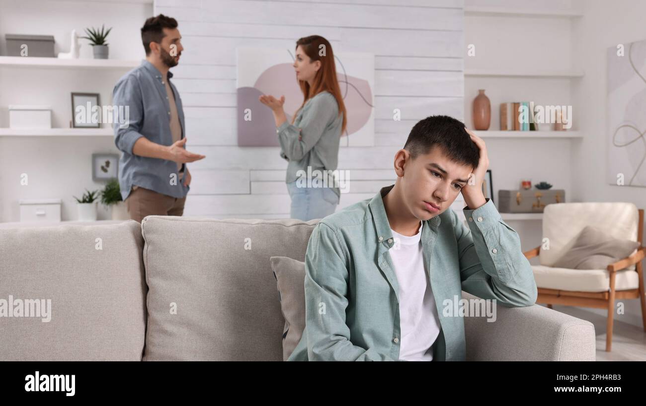 Couple arguing at home, focus on their unhappy teenage boy. Problems in ...