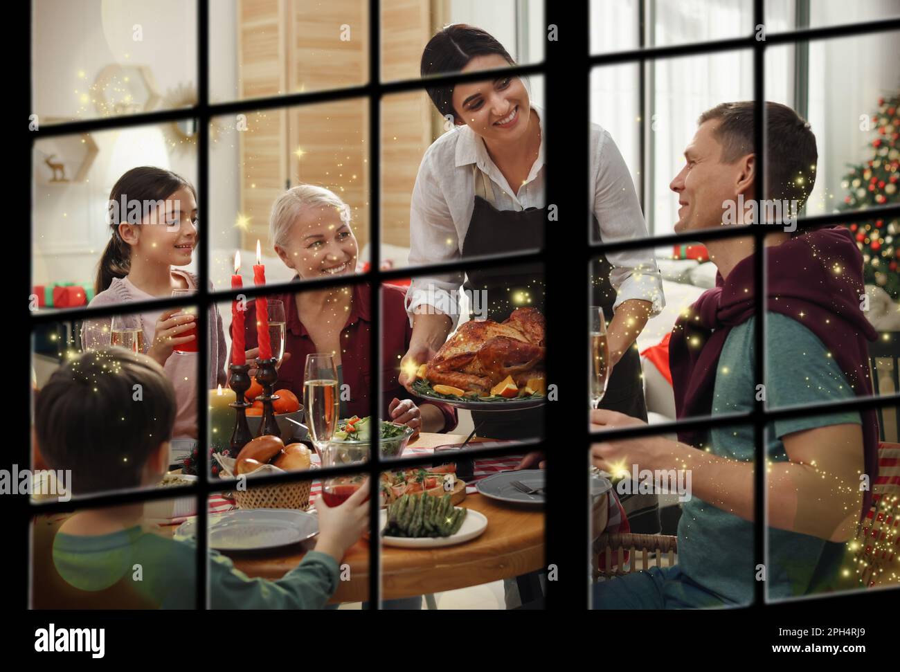 Happy family enjoying festive dinner at home, view through window ...