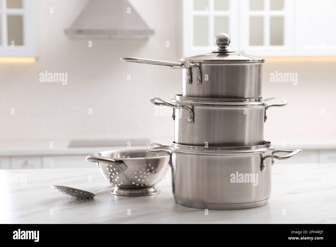 Set of stainless steel cookware and kitchen utensils on white table ...