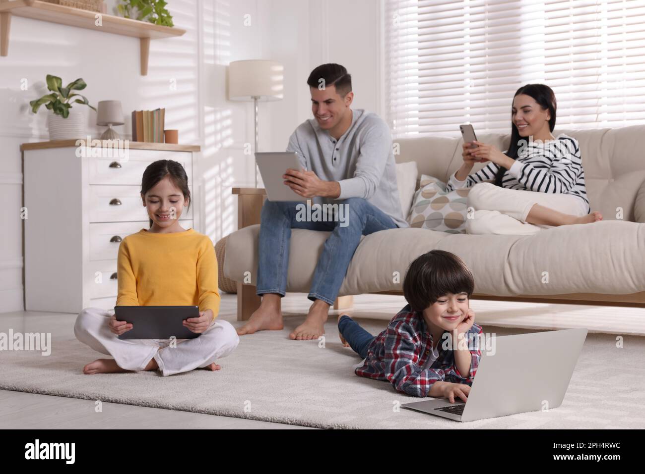 Internet addiction. Family with different gadgets in living room Stock ...