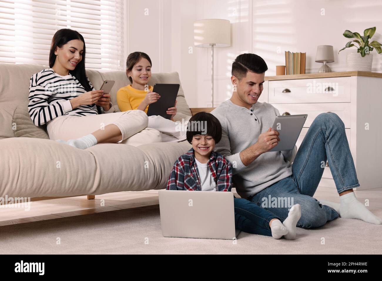 Internet addiction. Family with different gadgets in living room Stock ...