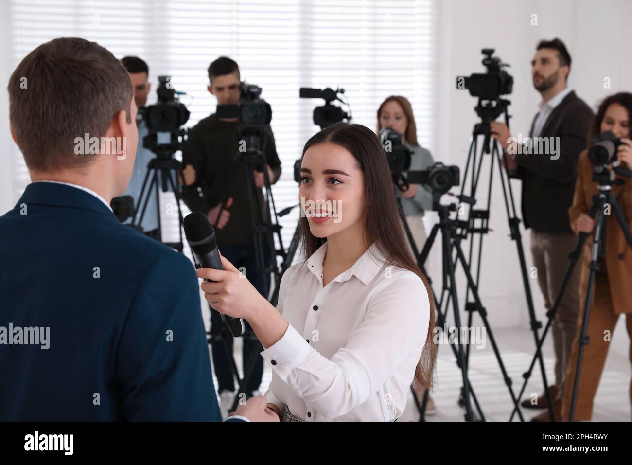 Professional young journalist interviewing businessman and group of ...