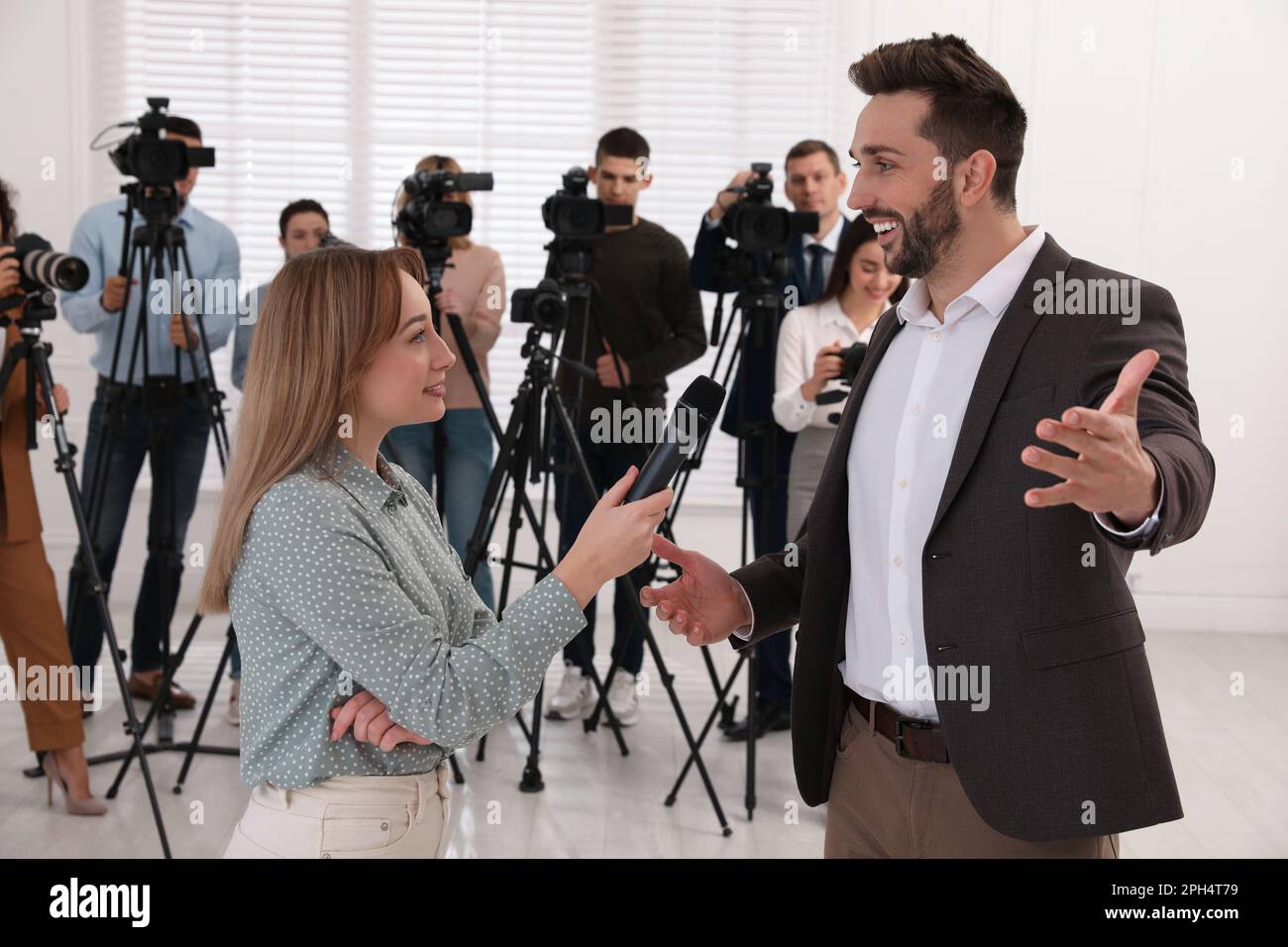 Professional young journalist interviewing businessman and group of ...