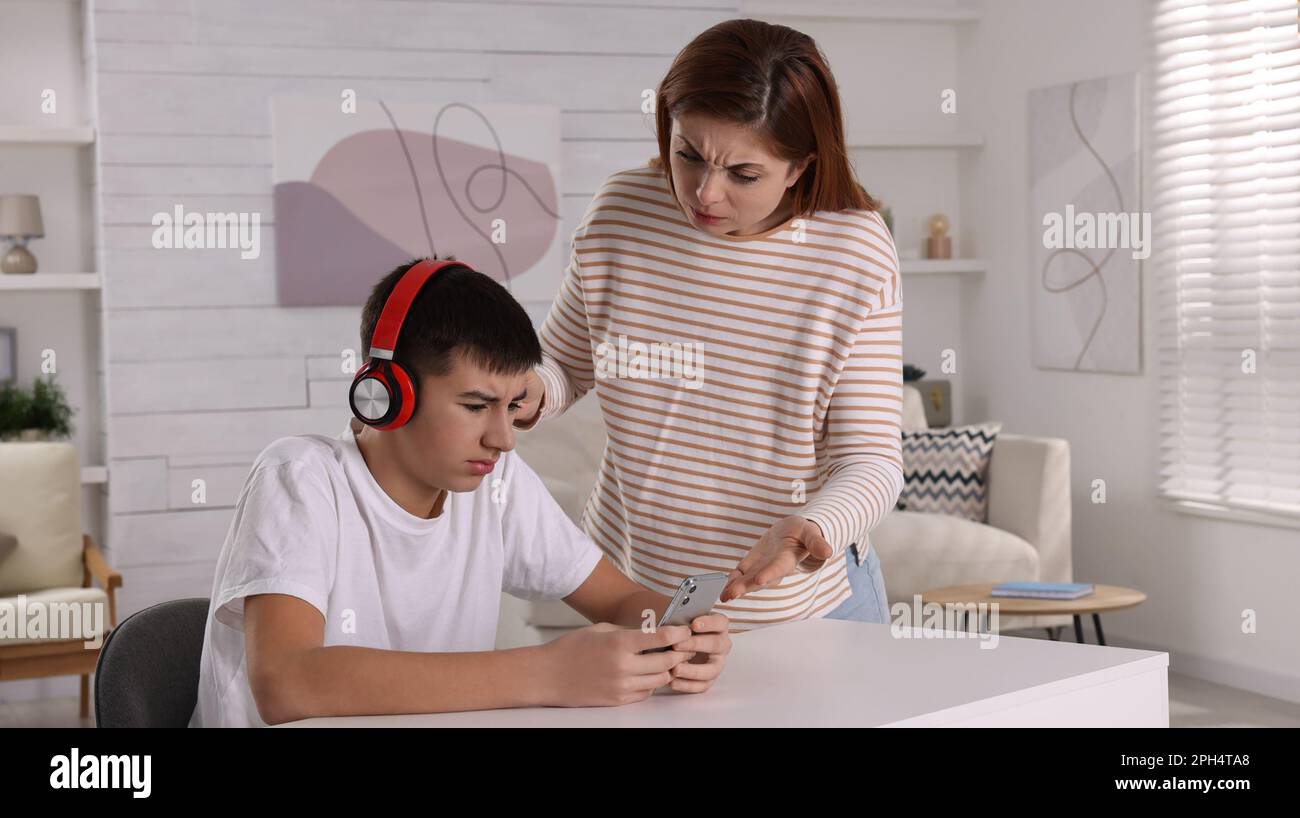 Mother scolding her son while he listening music in headphones at home ...