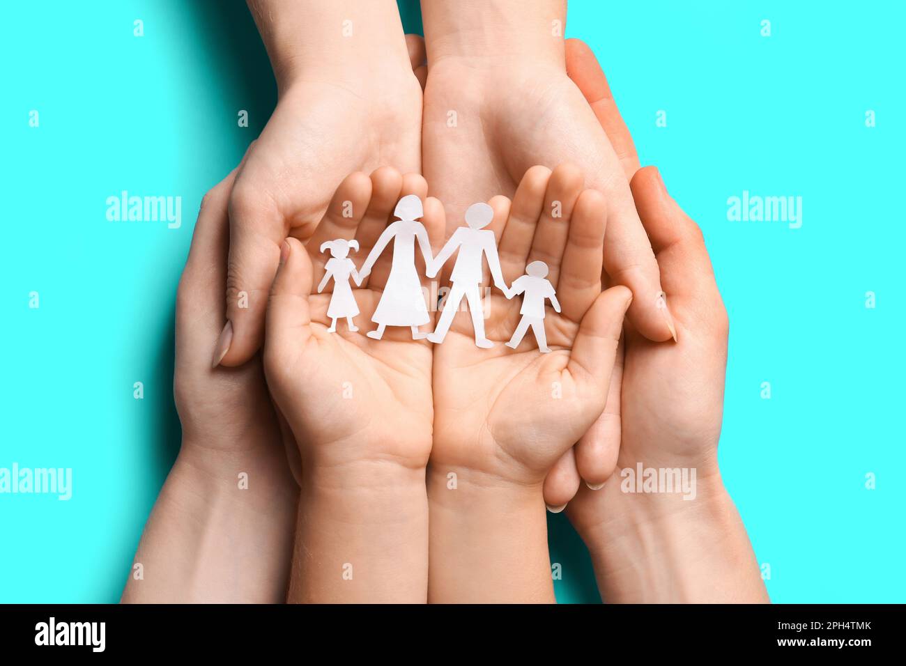 Parents and child holding paper cutout of family on light blue ...