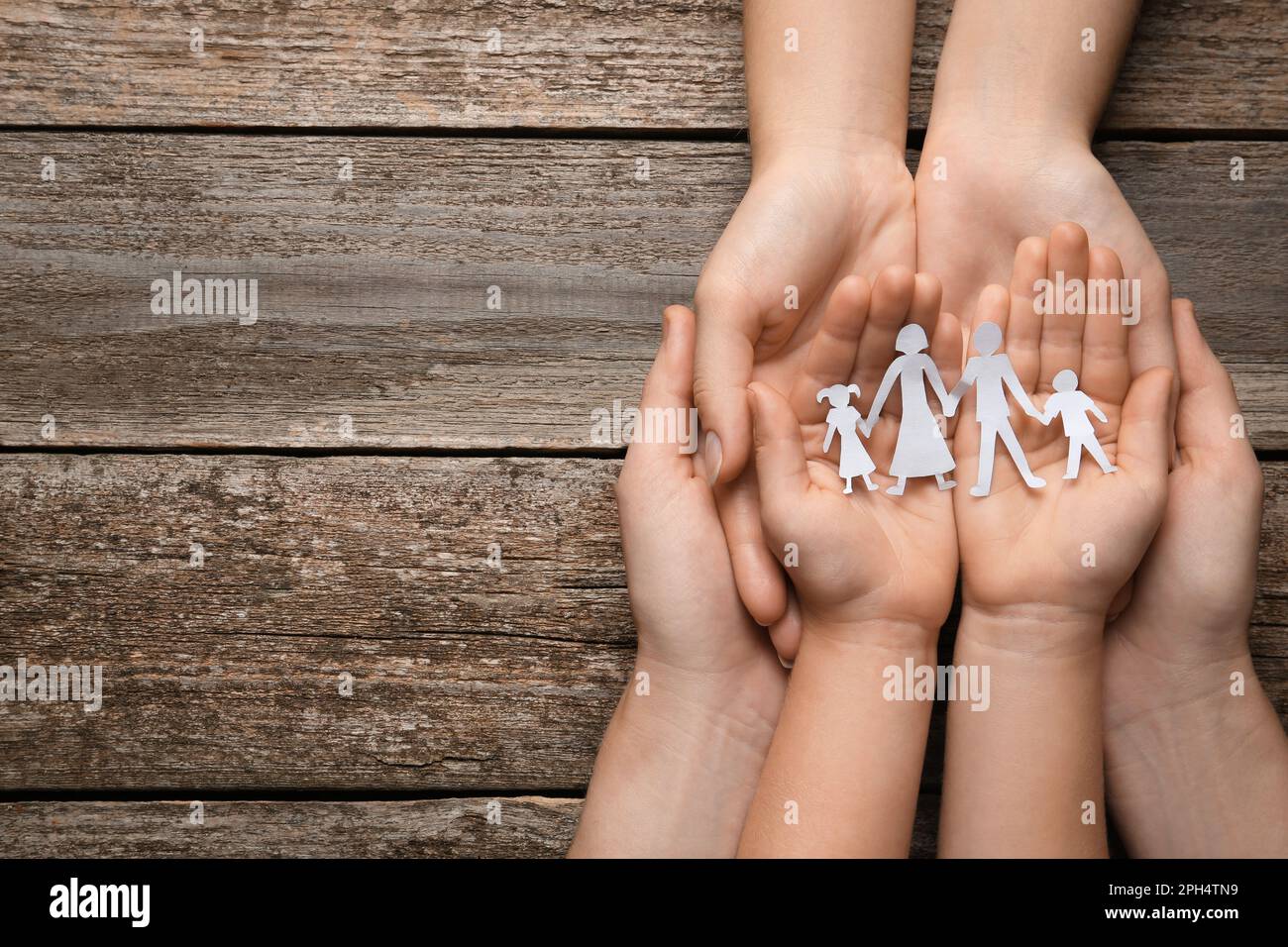 Parents and child holding paper cutout of family at wooden table, top ...