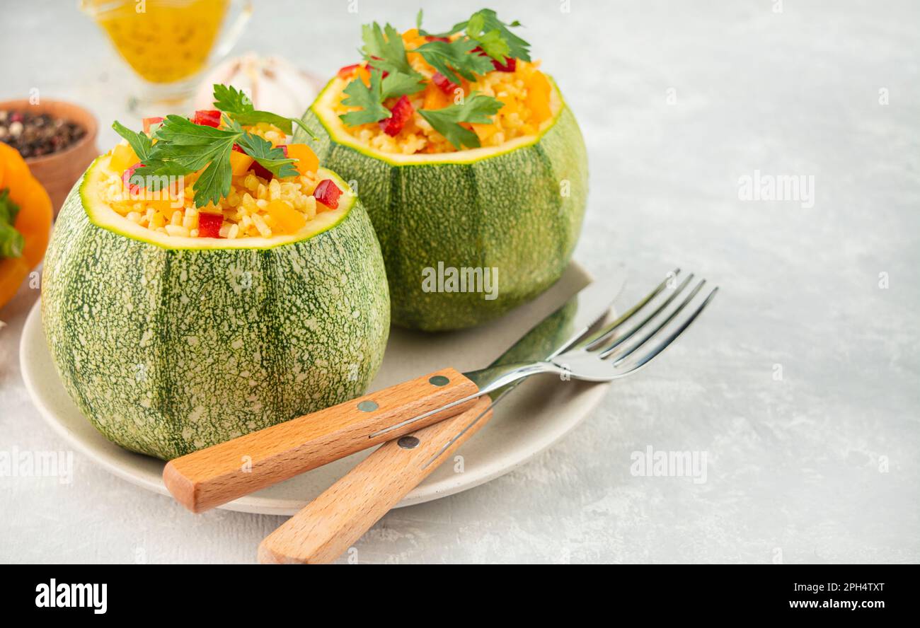 Stuffed zucchini with rice and vegetables on a light table. Side view ...