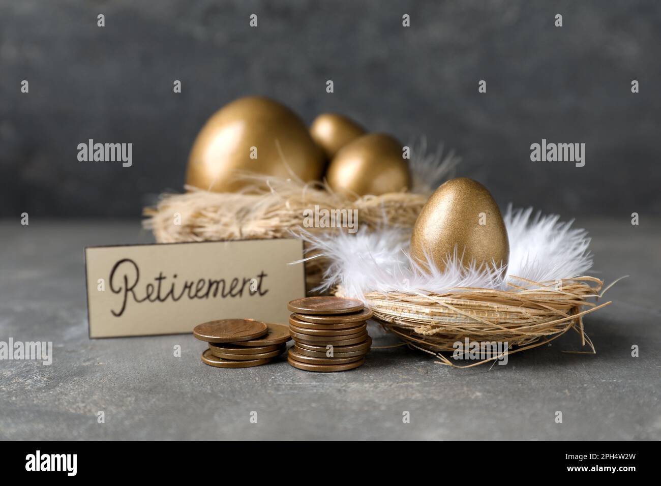 Many golden eggs, coins and card with word Retirement on grey table ...