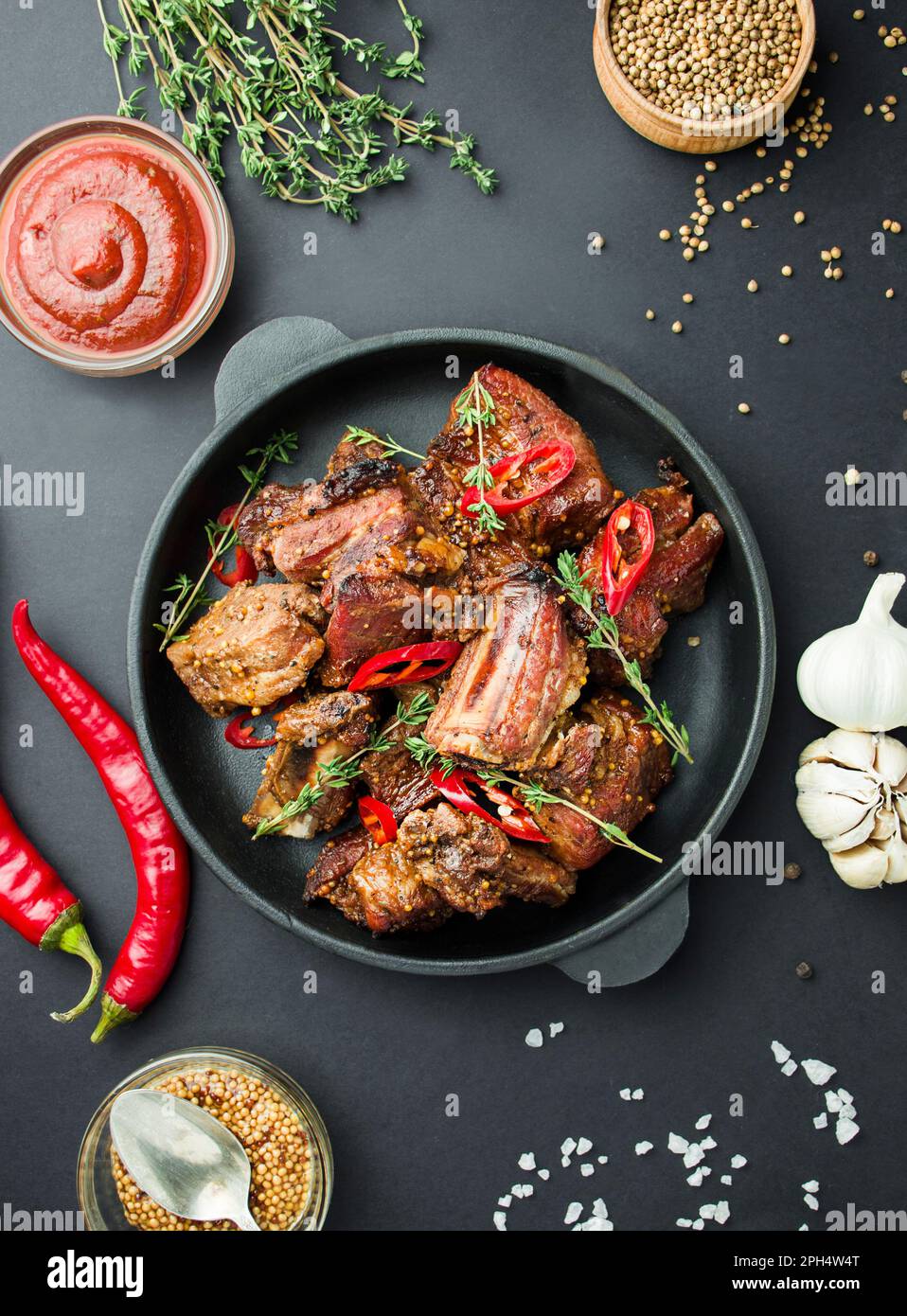 Baked ribs in a pan. Grilled pork ribs with spices and herbs on a dark ...