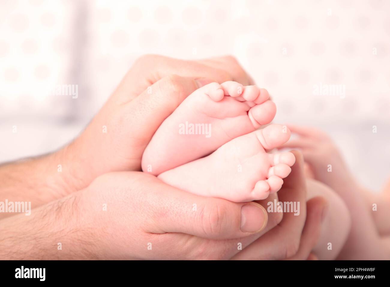 Father hands holding small baby feet on white bed. Top view Stock Photo ...