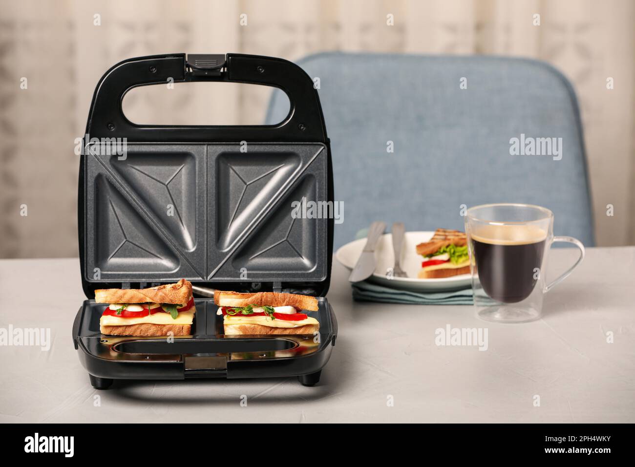 Modern grill maker with sandwiches and coffee on light grey table ...