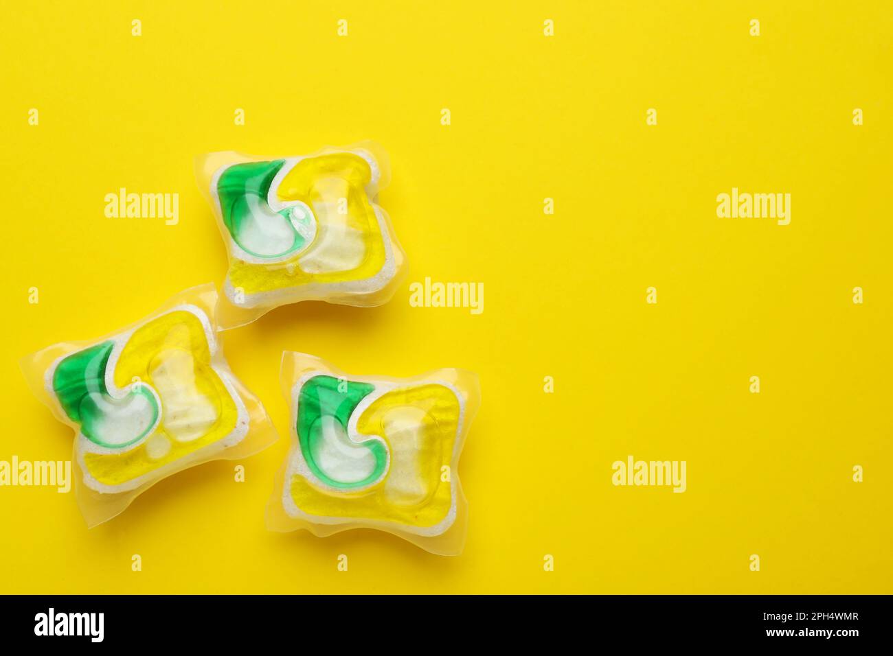 Dishwasher detergent pods on yellow background, flat lay. Space for ...