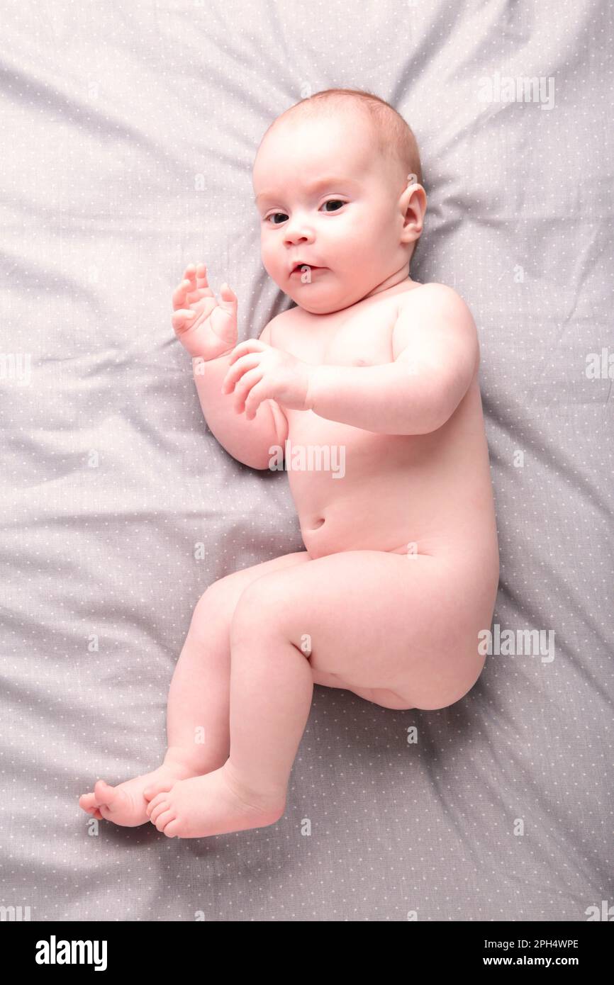 Pretty baby girl lying on grey bed, top view Stock Photo - Alamy
