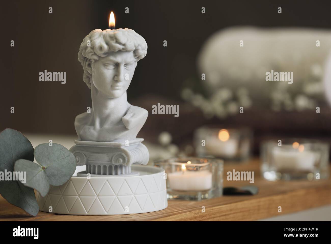 Beautiful David bust candle and eucalyptus branch on wooden table in ...