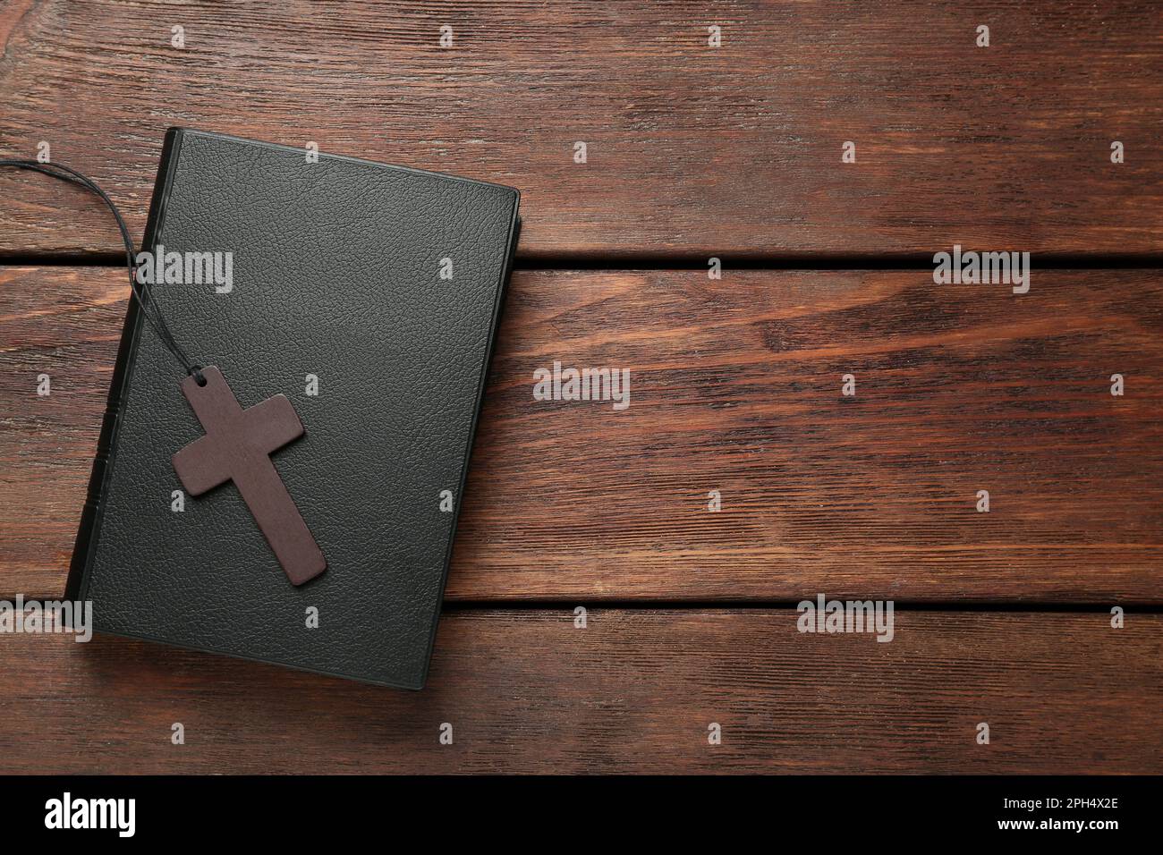 Wooden Christian cross and Bible on table, top view. Space for text ...