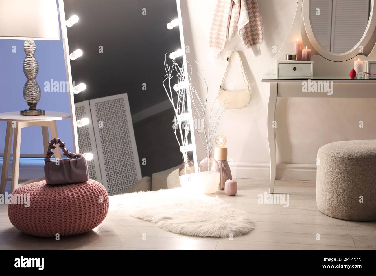Large mirror with light bulbs and dressing table in stylish room ...