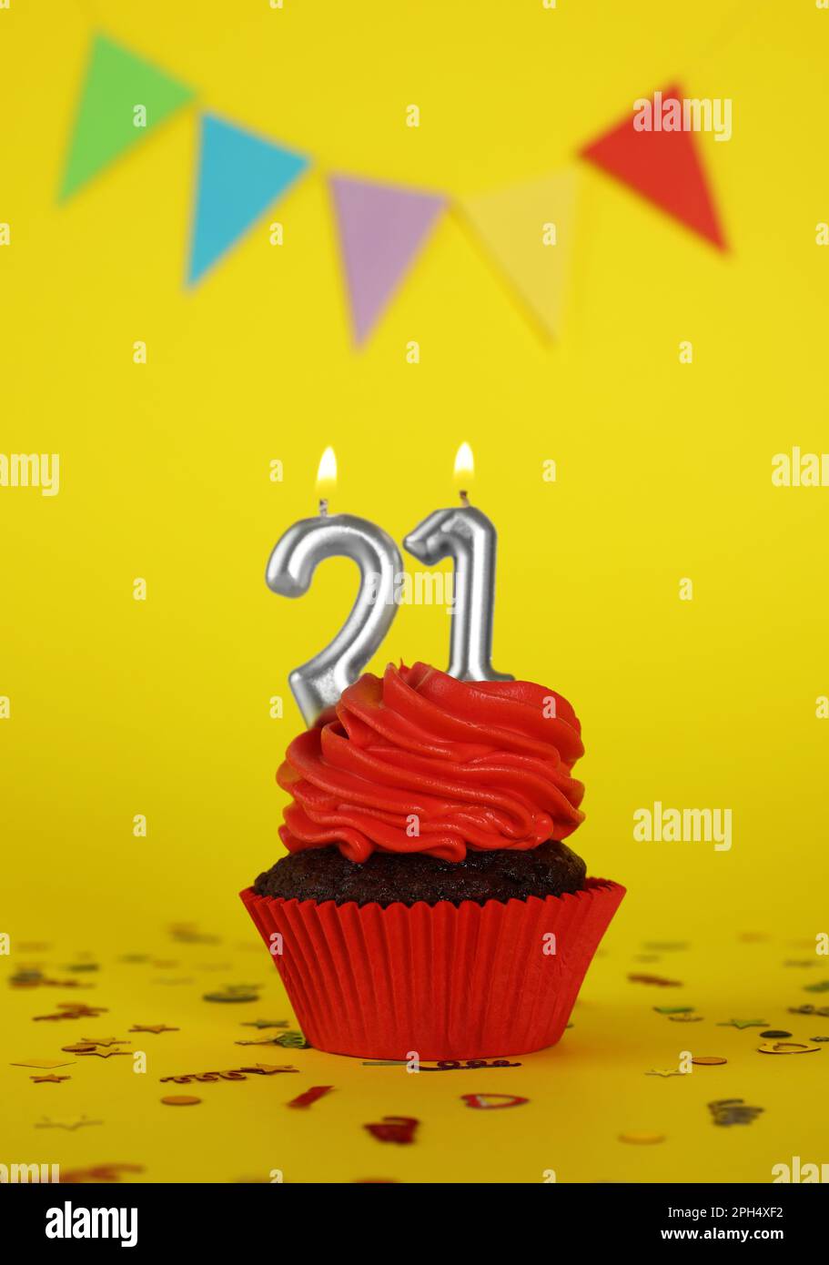 Delicious cupcake with number shaped candles on yellow background ...