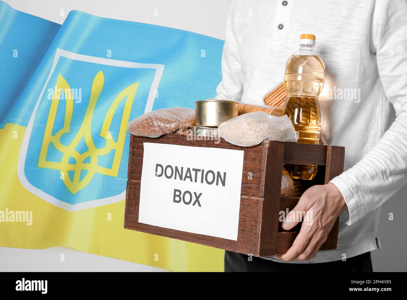 Volunteer holding donation box with Ukrainian flag on background. Help ...