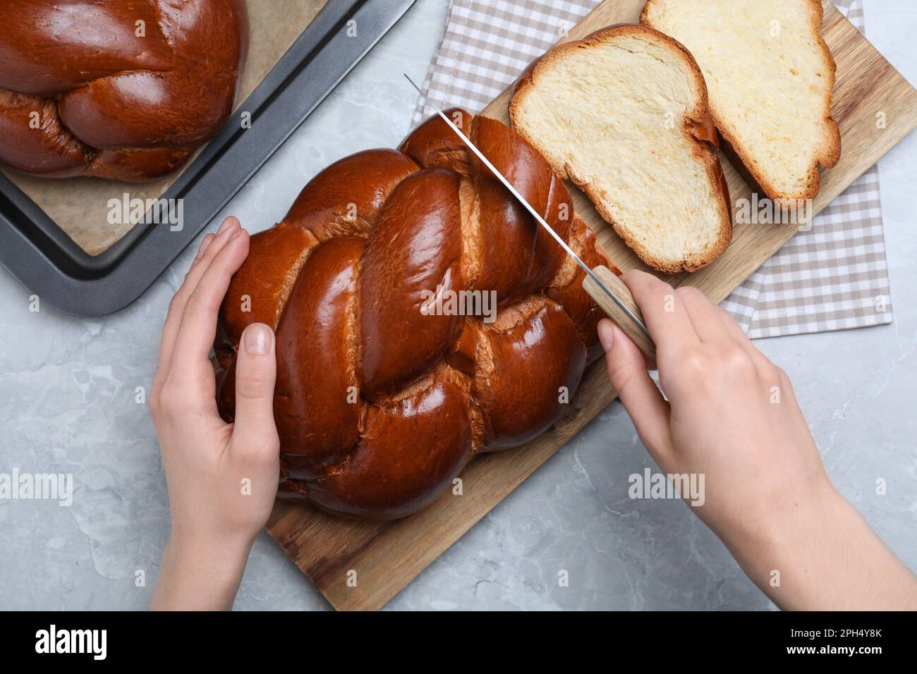 Woman cutting homemade braided bread at grey table, top view. Traditional Shabbat challah Stock ...