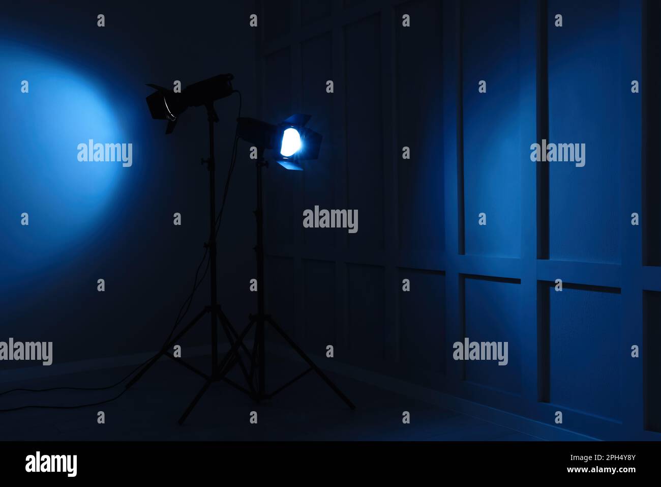 Bright blue spotlights near wall in dark room, space for text Stock ...