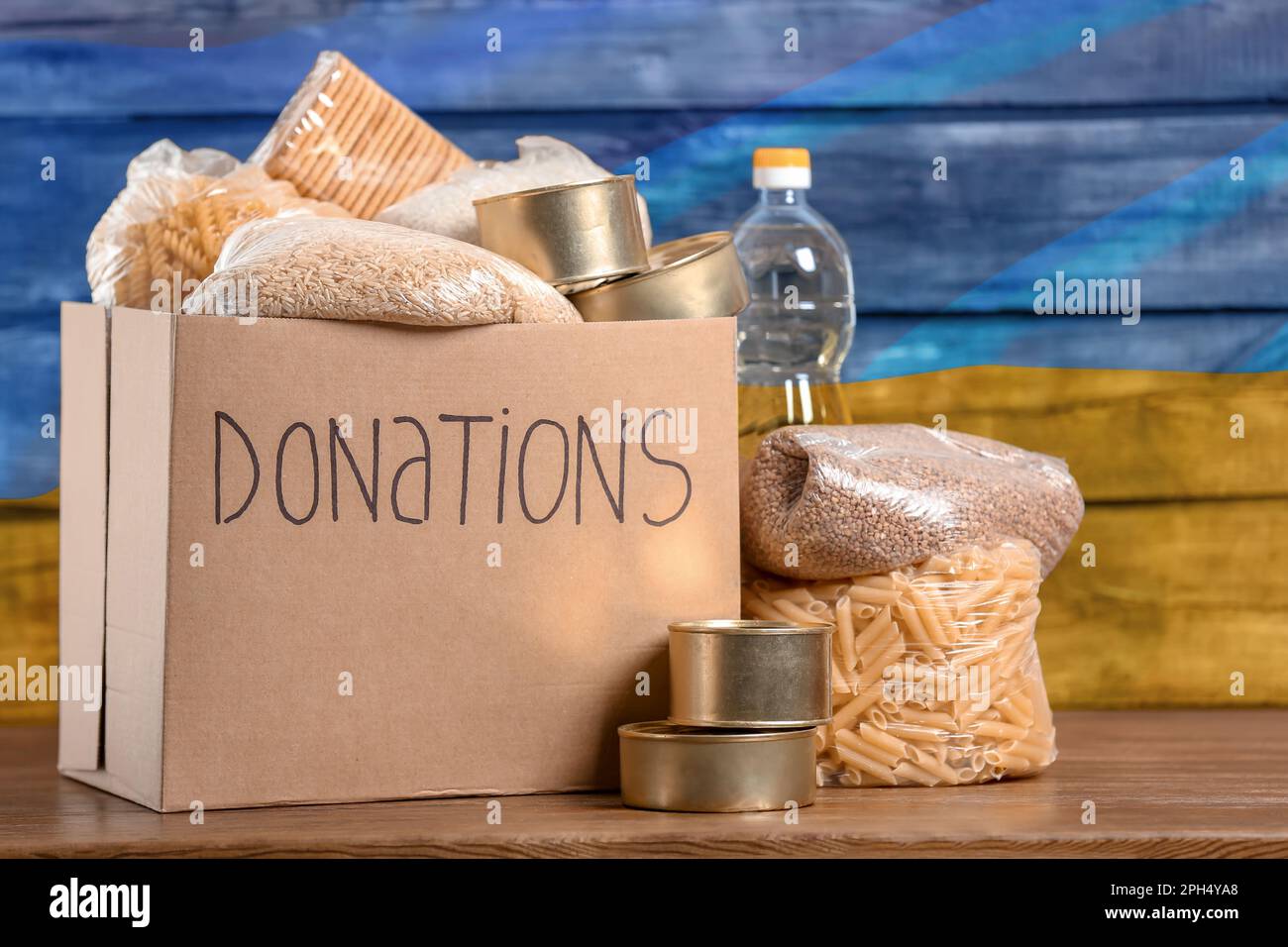 Donation box, different products and Ukrainian flag on background. Help ...