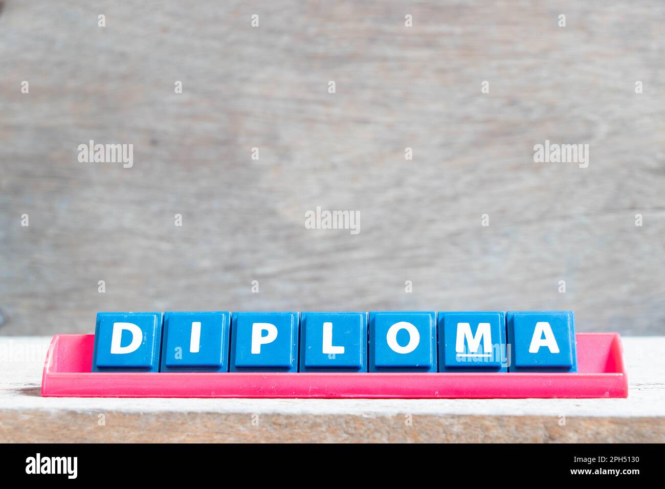 Tile alphabet letter with word diploma in red color rack on wood ...