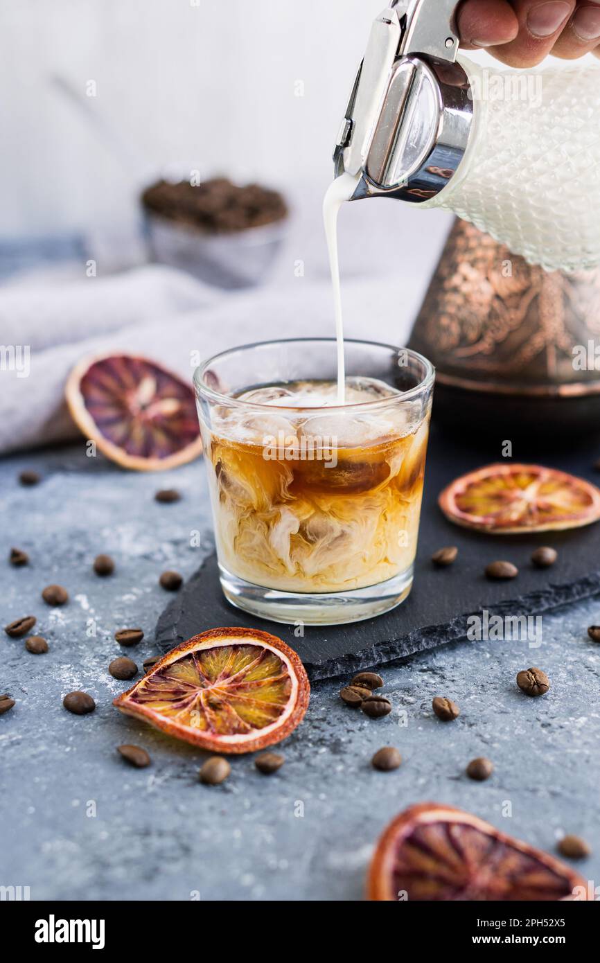 Iced coffee with milk. Summer drink. Pouring milk in coffee with ice ...
