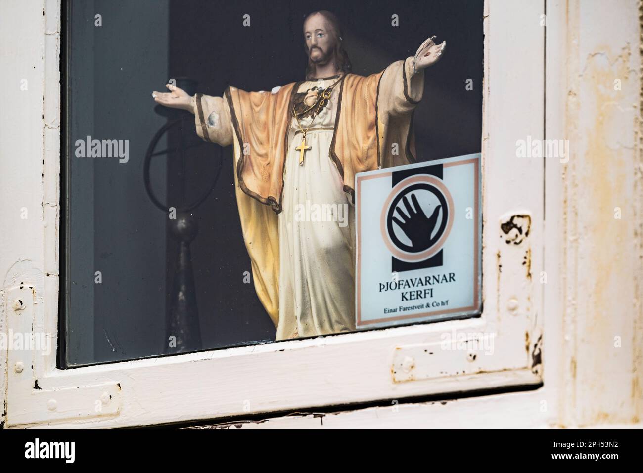 Small wooden Jesus statue standing behind one of the windows of ...