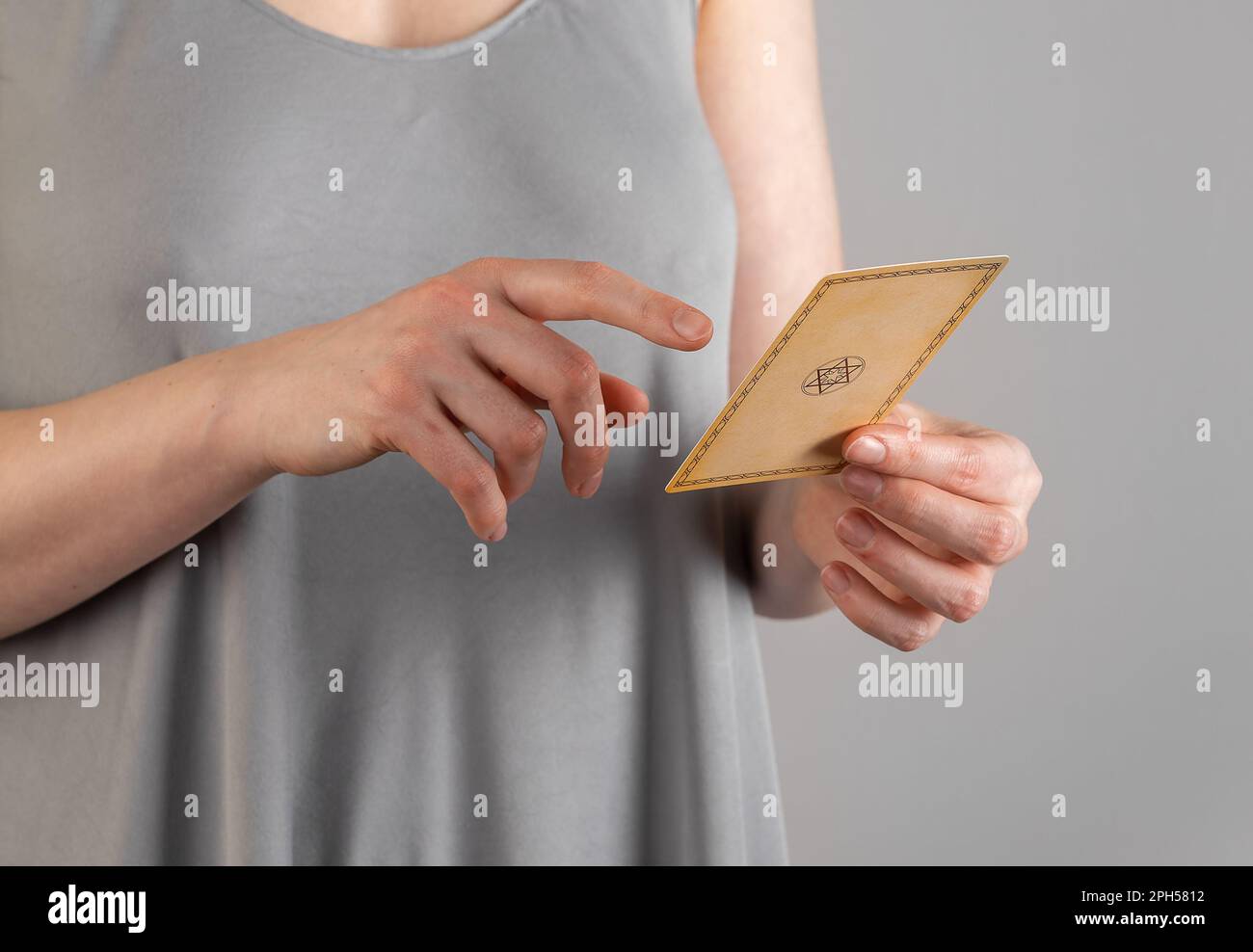 Hand holding abstract tarot card, pointing with finger on it, telling ...