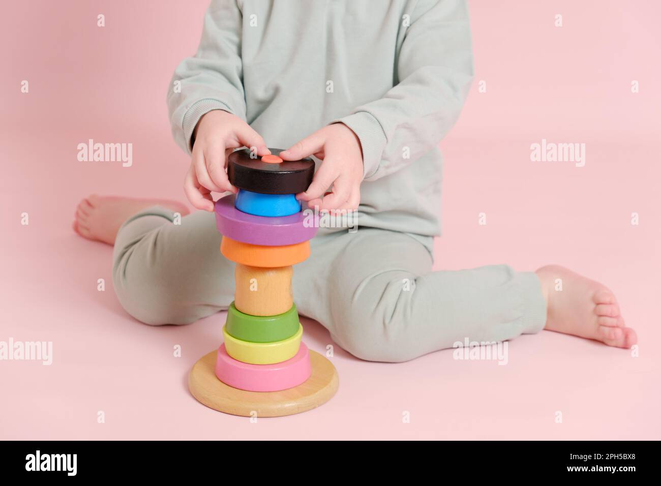 Happy toddler baby plays with a pyramid on a studio pink background ...