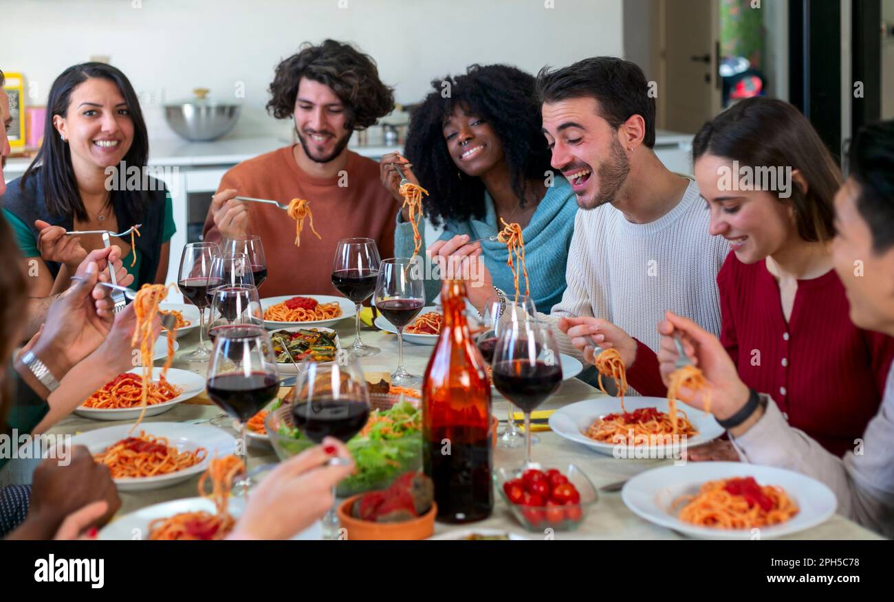 Friends are planning a dinner at home. They are laughing while eating ...