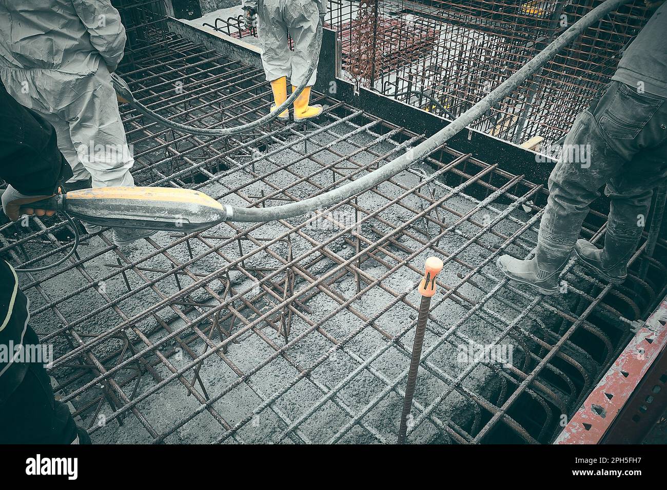 Construction workers dressed in protective workwear use concrete ...