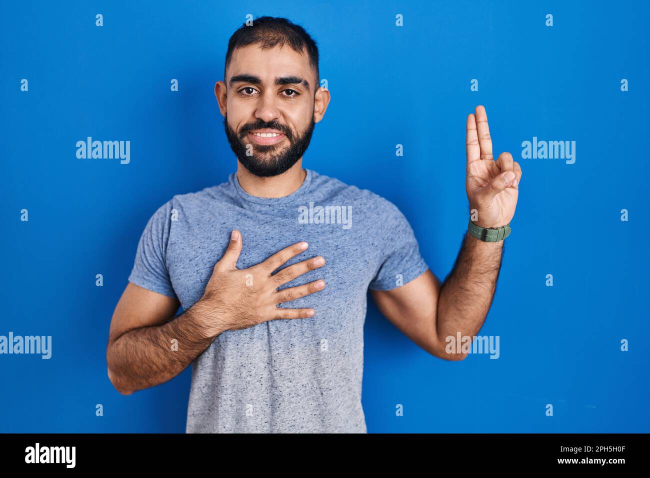 Middle east man with beard standing over blue background smiling ...