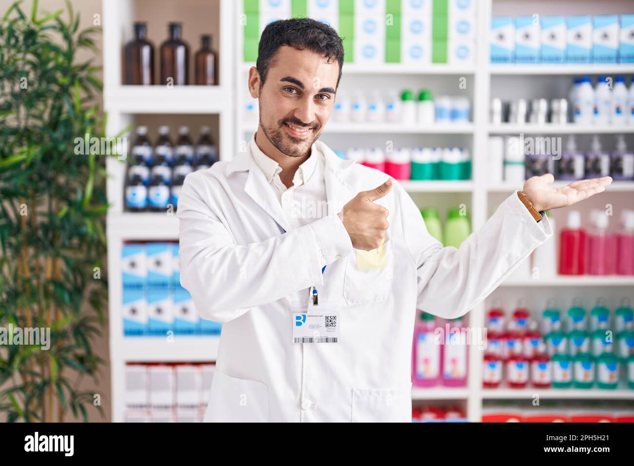 Handsome hispanic man working at pharmacy drugstore showing palm hand ...