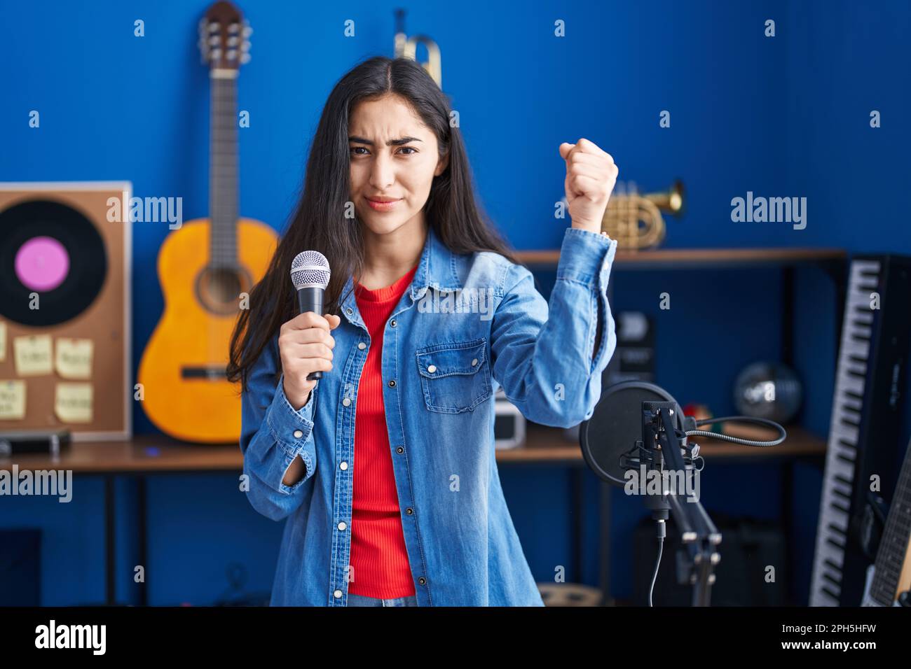 Young teenager girl singing song using microphone annoyed and ...