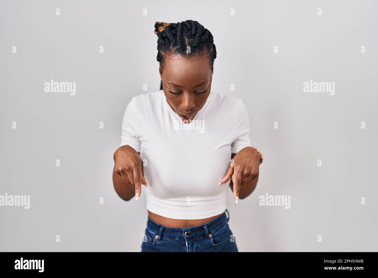 Beautiful black woman standing over isolated background pointing down ...