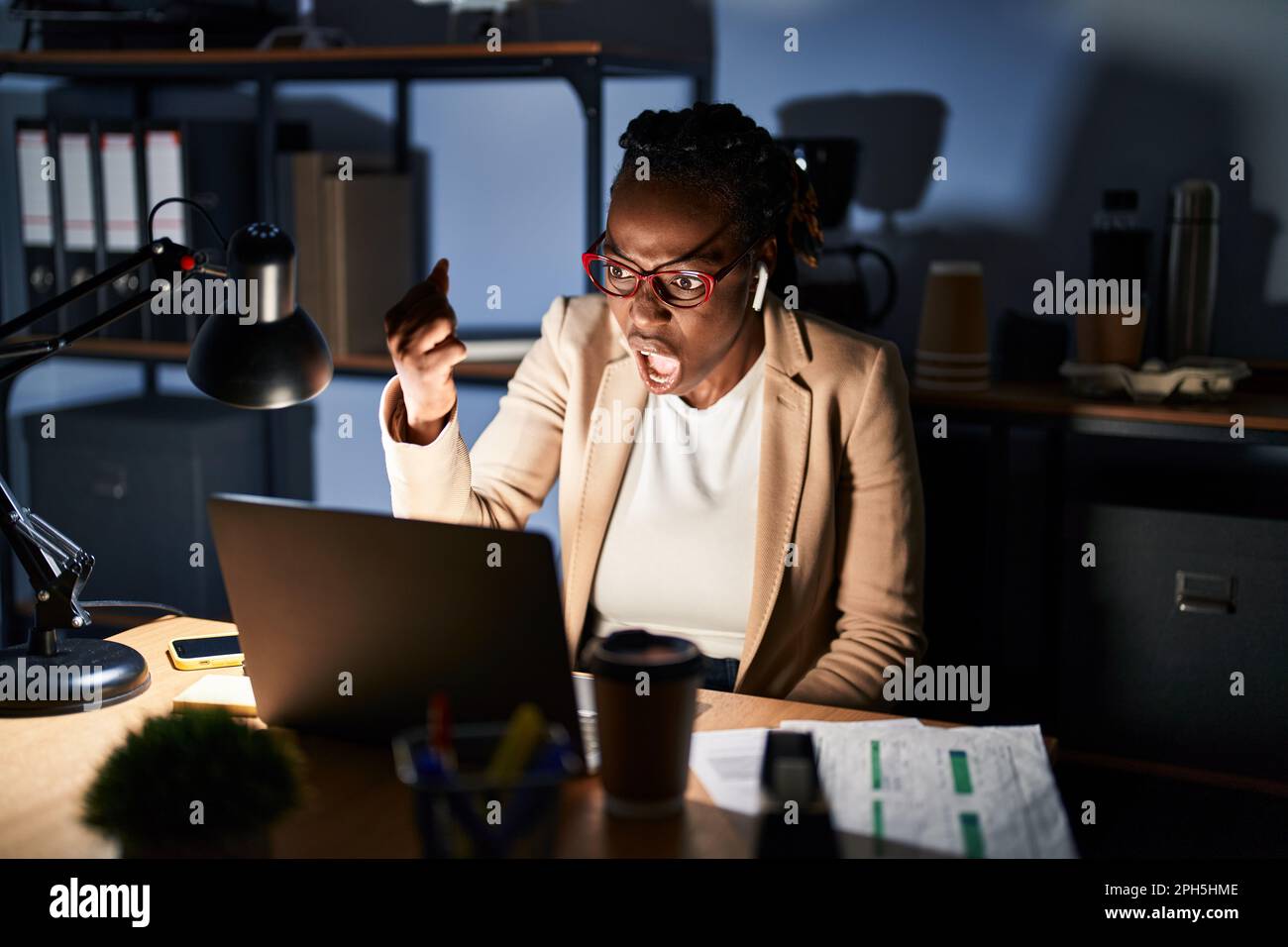 Beautiful black woman working at the office at night angry and mad ...