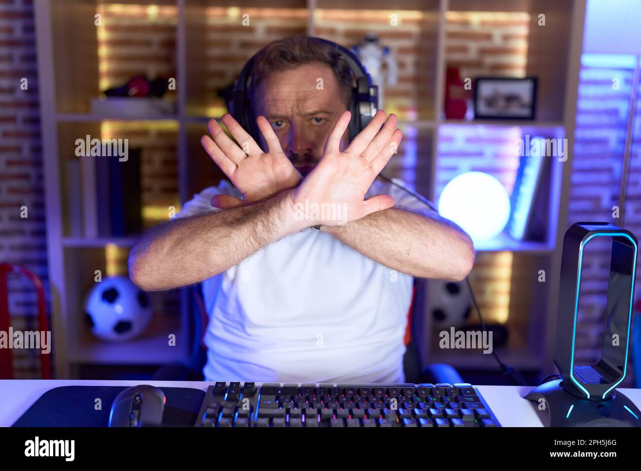 Middle age man with beard playing video games wearing headphones ...