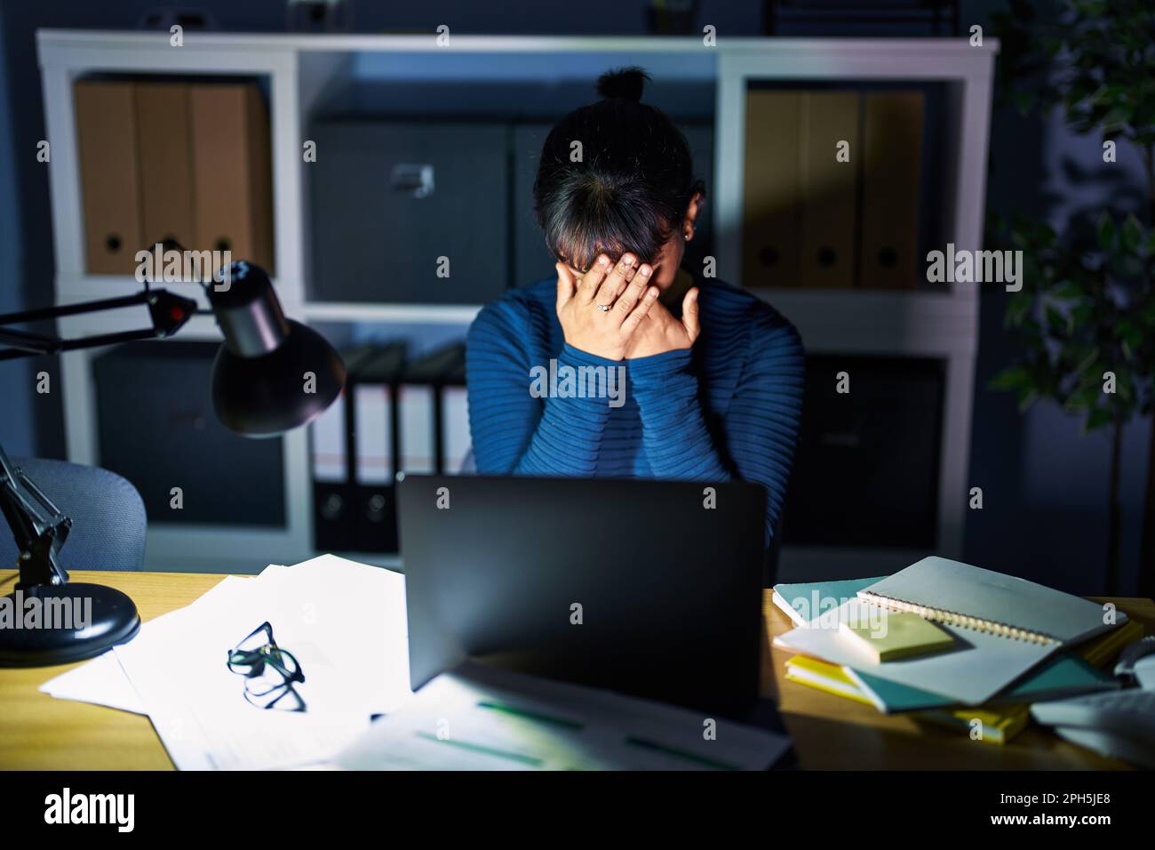 Young beautiful woman working at the office at night with sad ...
