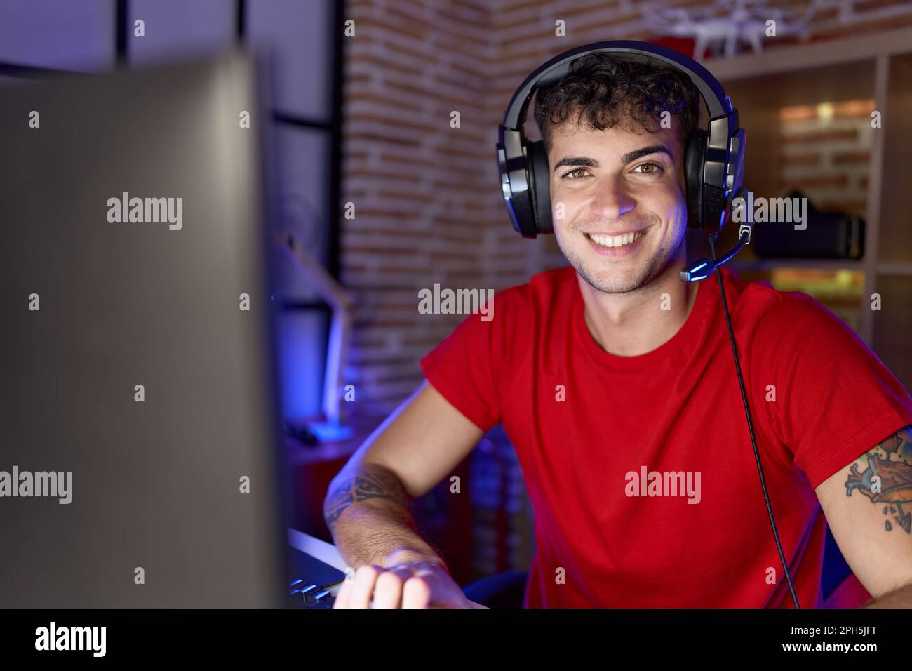 Young hispanic man streamer playing video game using computer at gaming ...