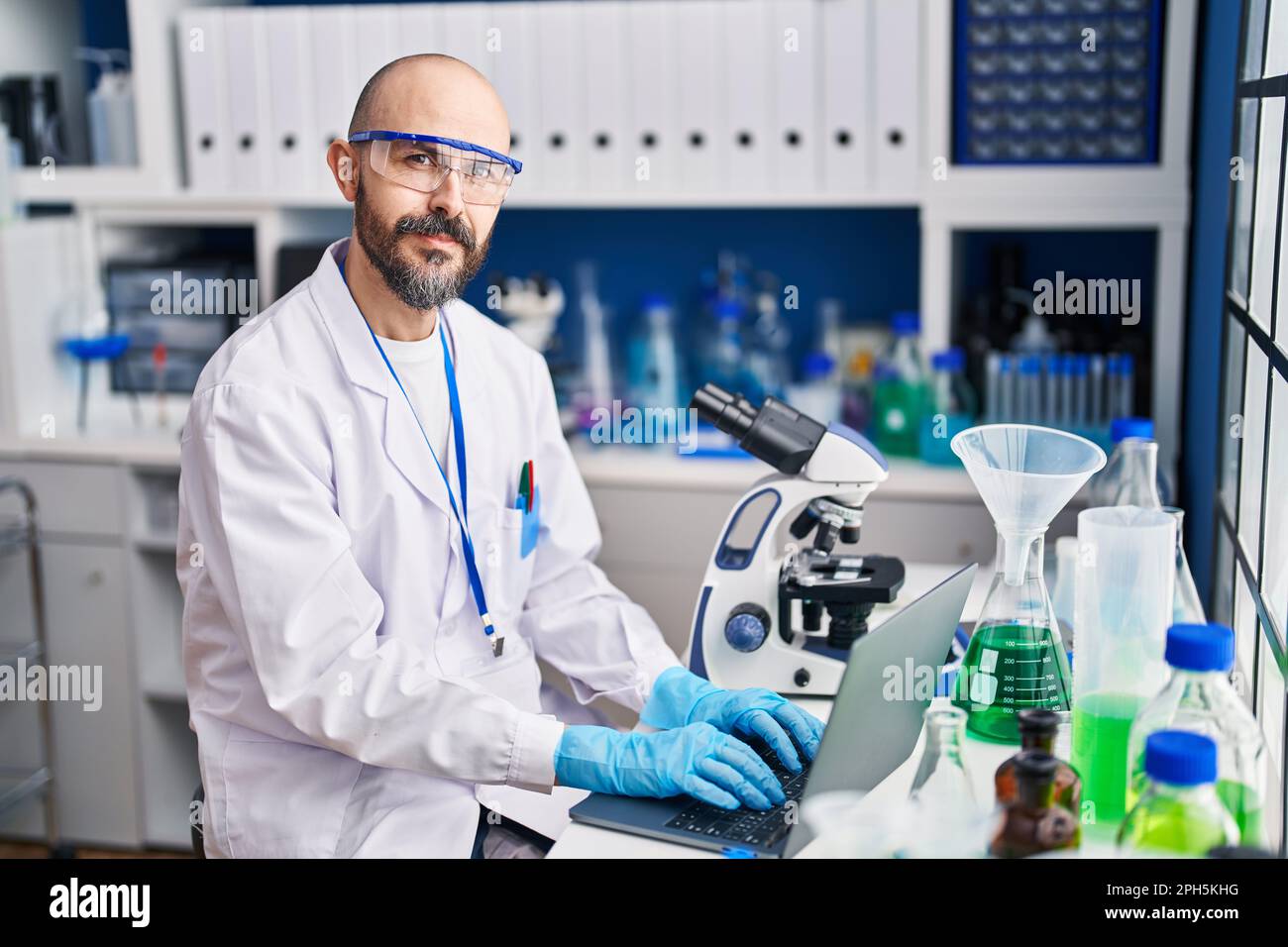 Young bald man scientist using laptop at laboratory Stock Photo - Alamy