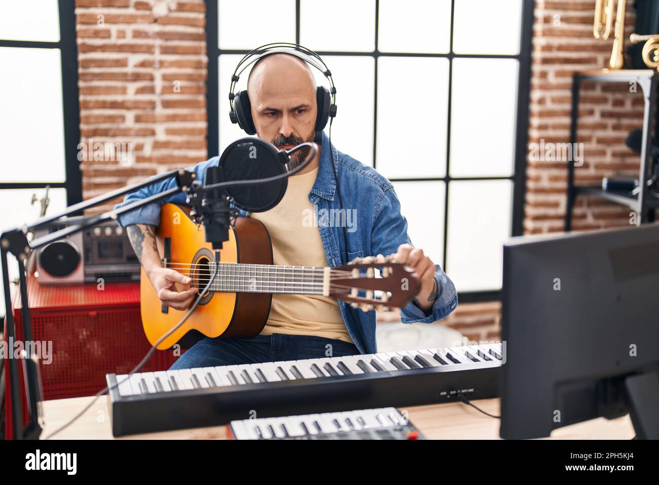 Young bald man musician playing classical guitar at music studio Stock ...