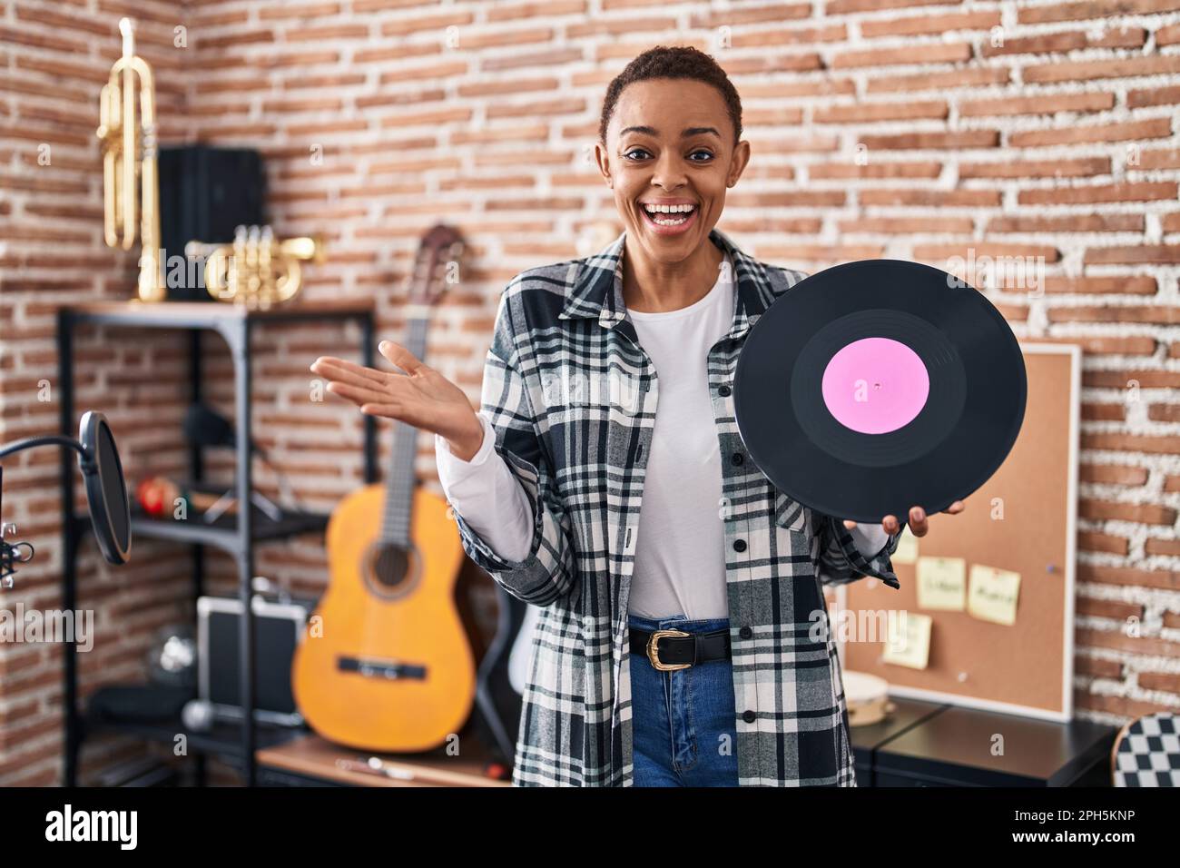 Beautiful african american woman holding vinyl record at music studio ...