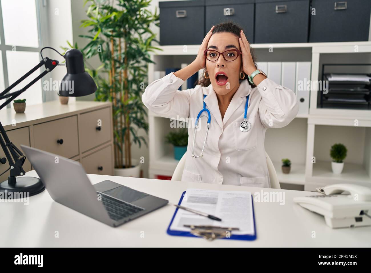 Young hispanic woman wearing doctor uniform and stethoscope crazy and ...