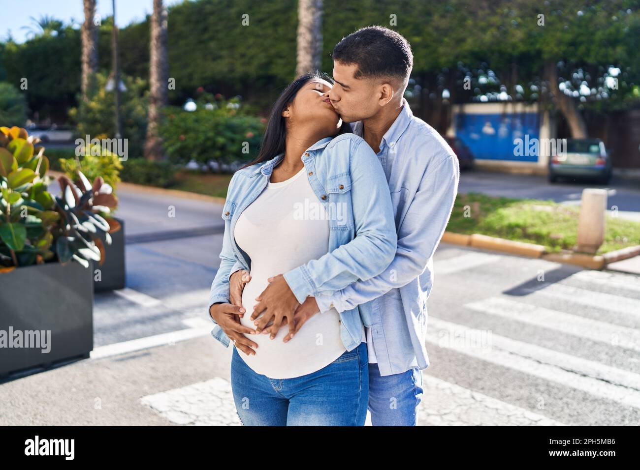 Young latin couple expecting baby hugging each other and kissing at street Stock Photo - Alamy